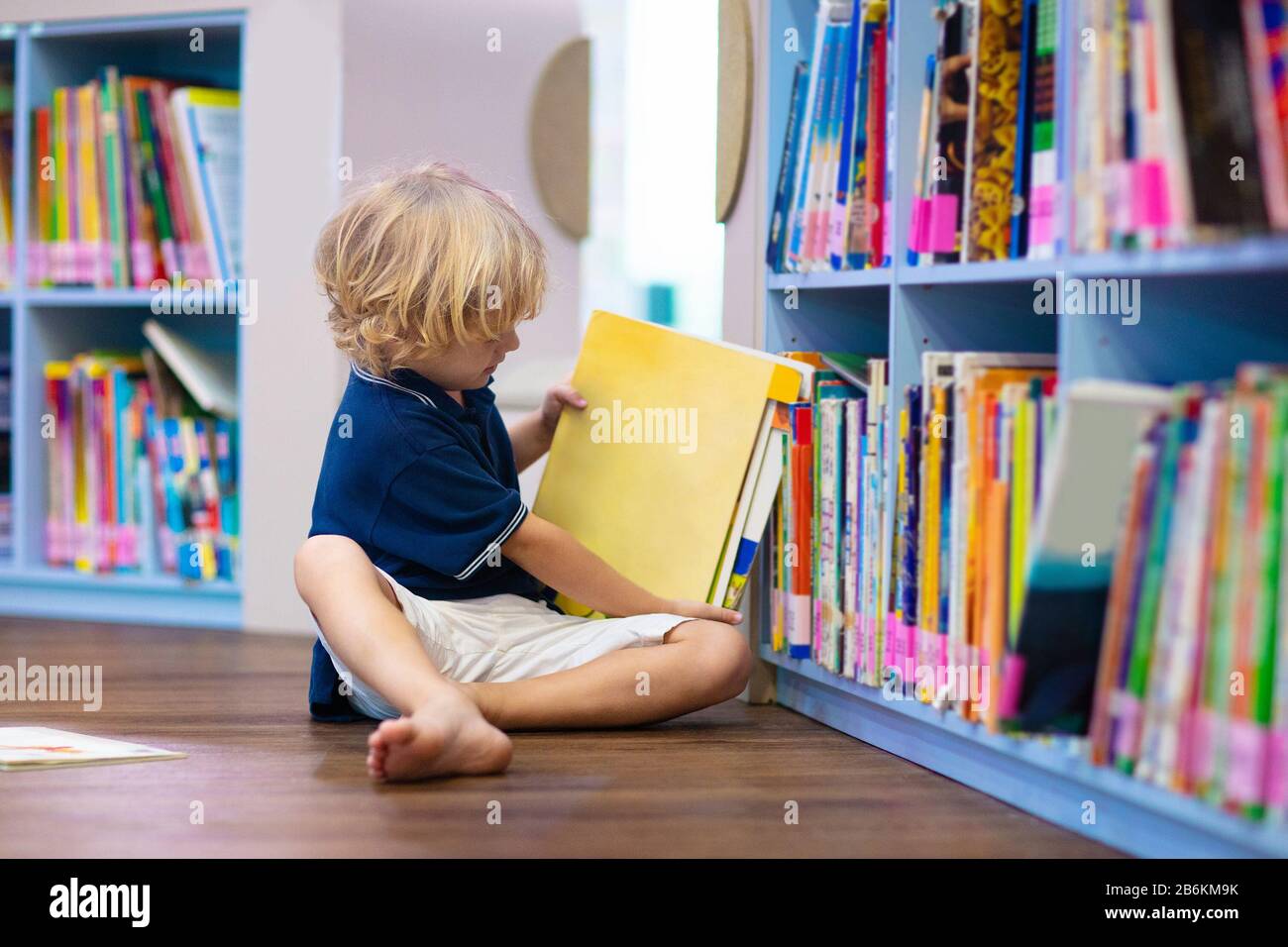 Child in school library. Kids read books. Little boy reading and ...