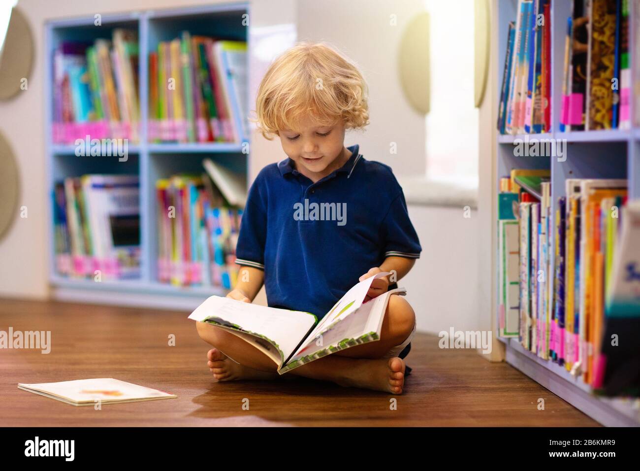 Child in school library. Kids read books. Little boy reading and ...