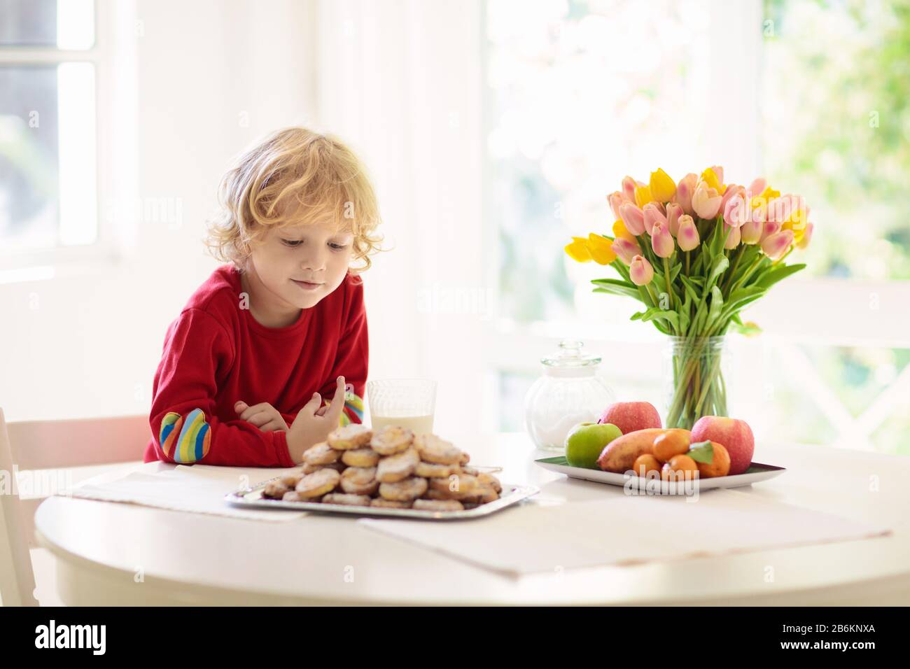 Child eating breakfast. Kid drinking milk with fresh homemade cookies ...