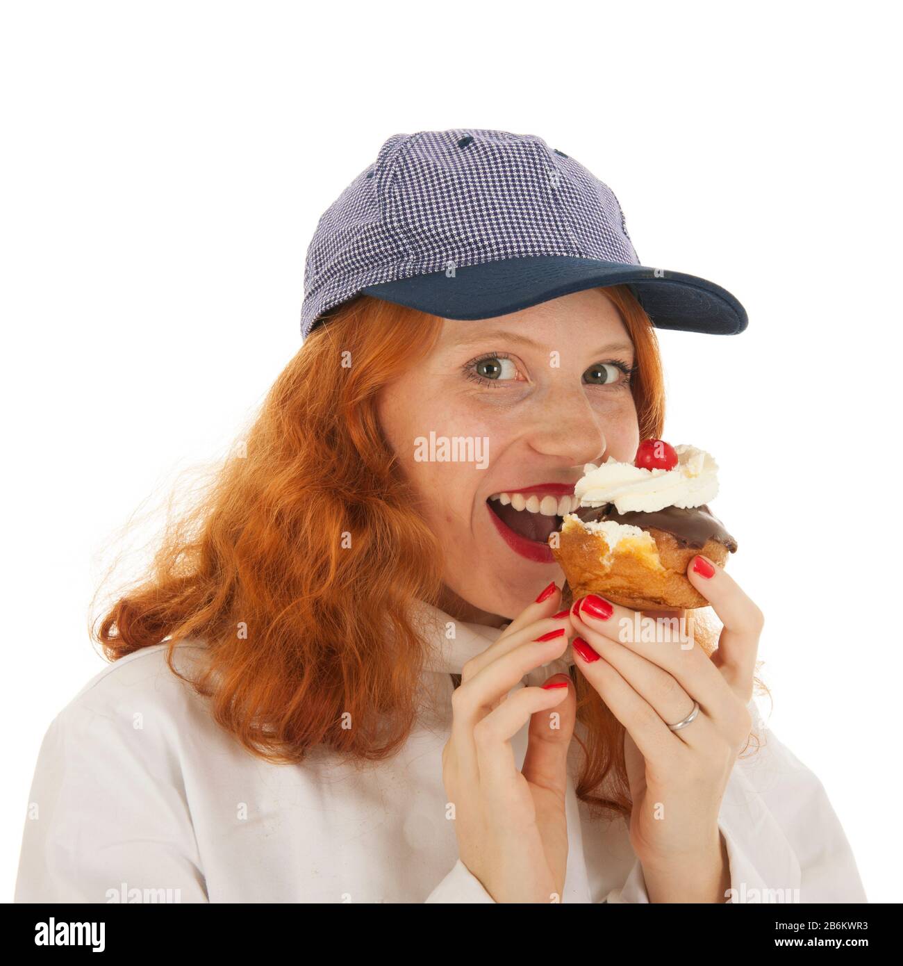 Female baker chef with red hair eating pastry isolated over white ...