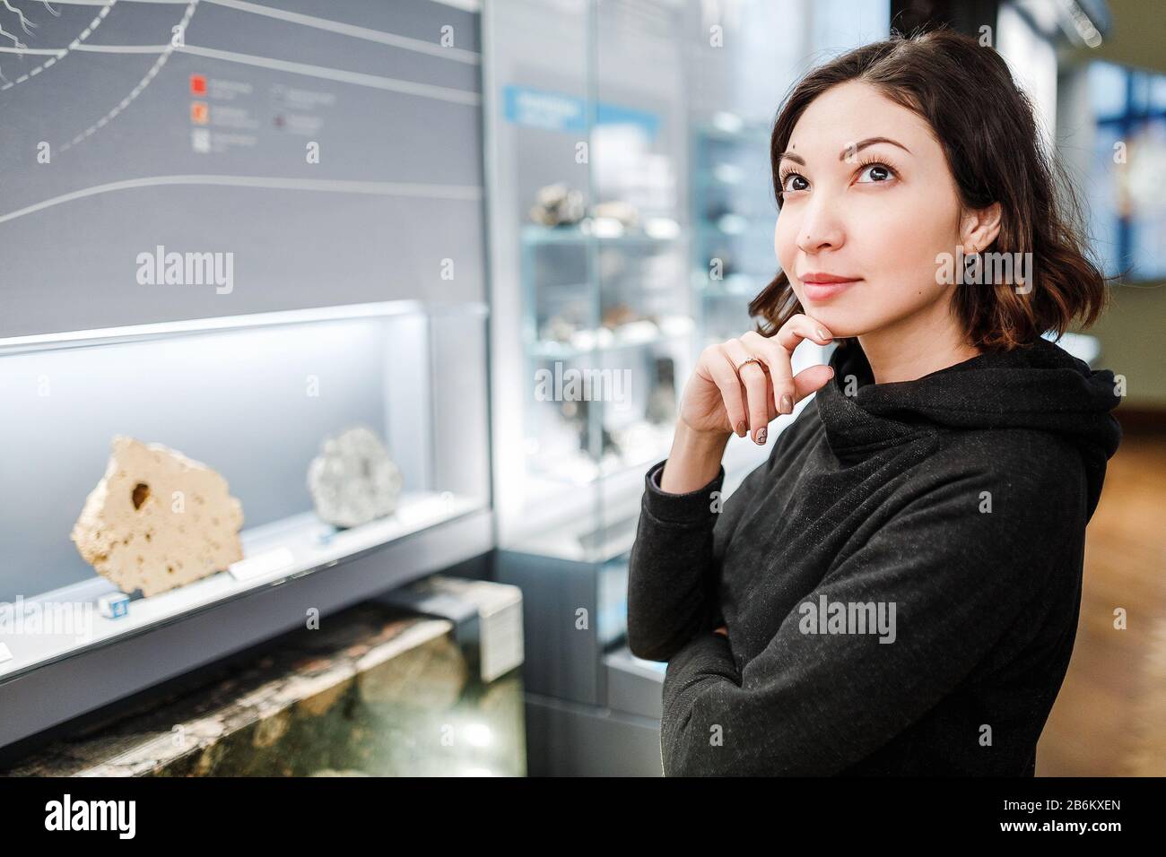 Beautiful Asian happy geologist woman indoors looking at minerals ...