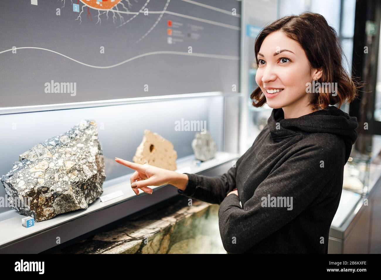 Beautiful Asian happy geologist woman indoors looking at minerals ...