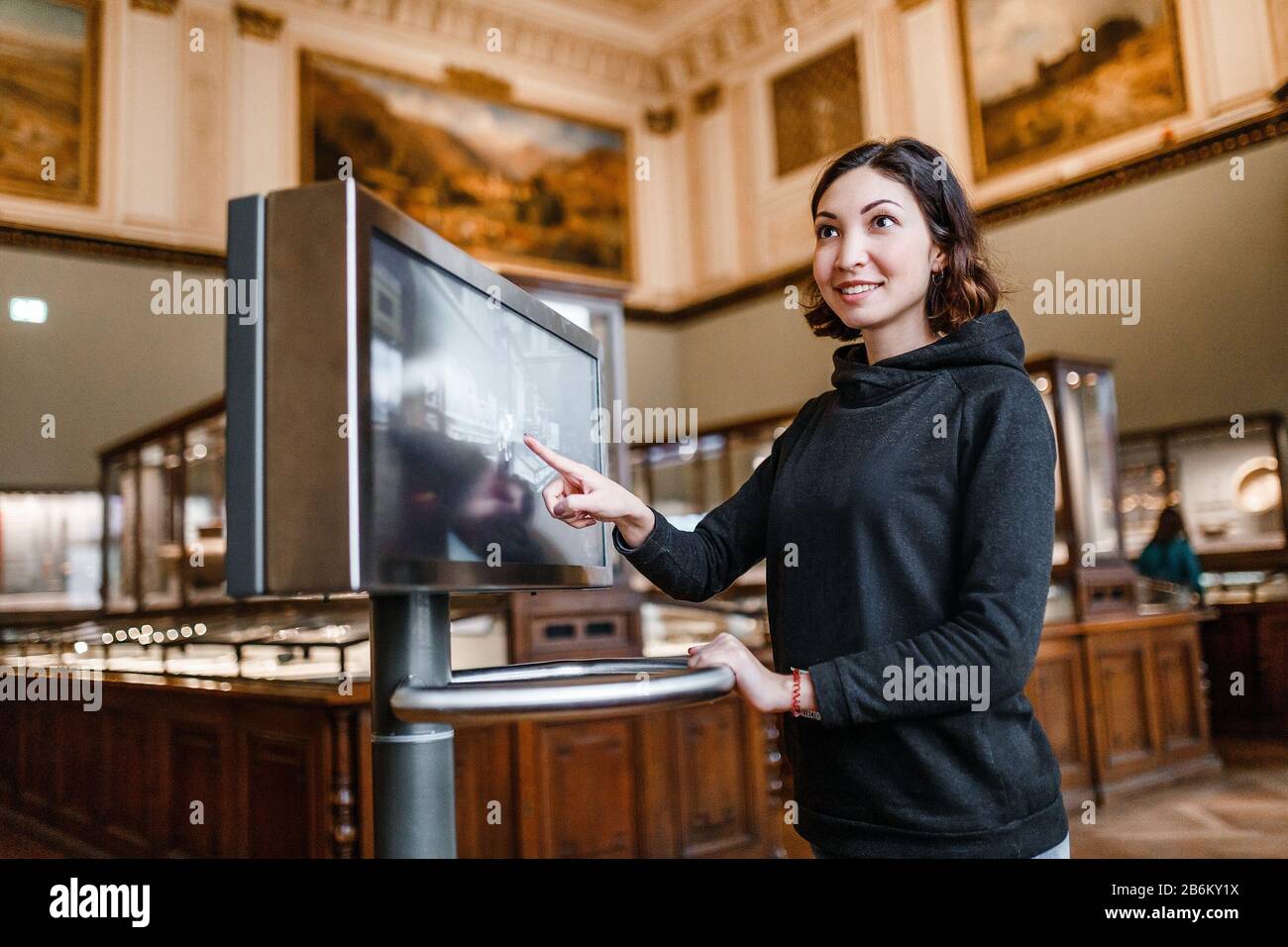 A woman in the museum uses the touchscreen monitor electronic guide ...