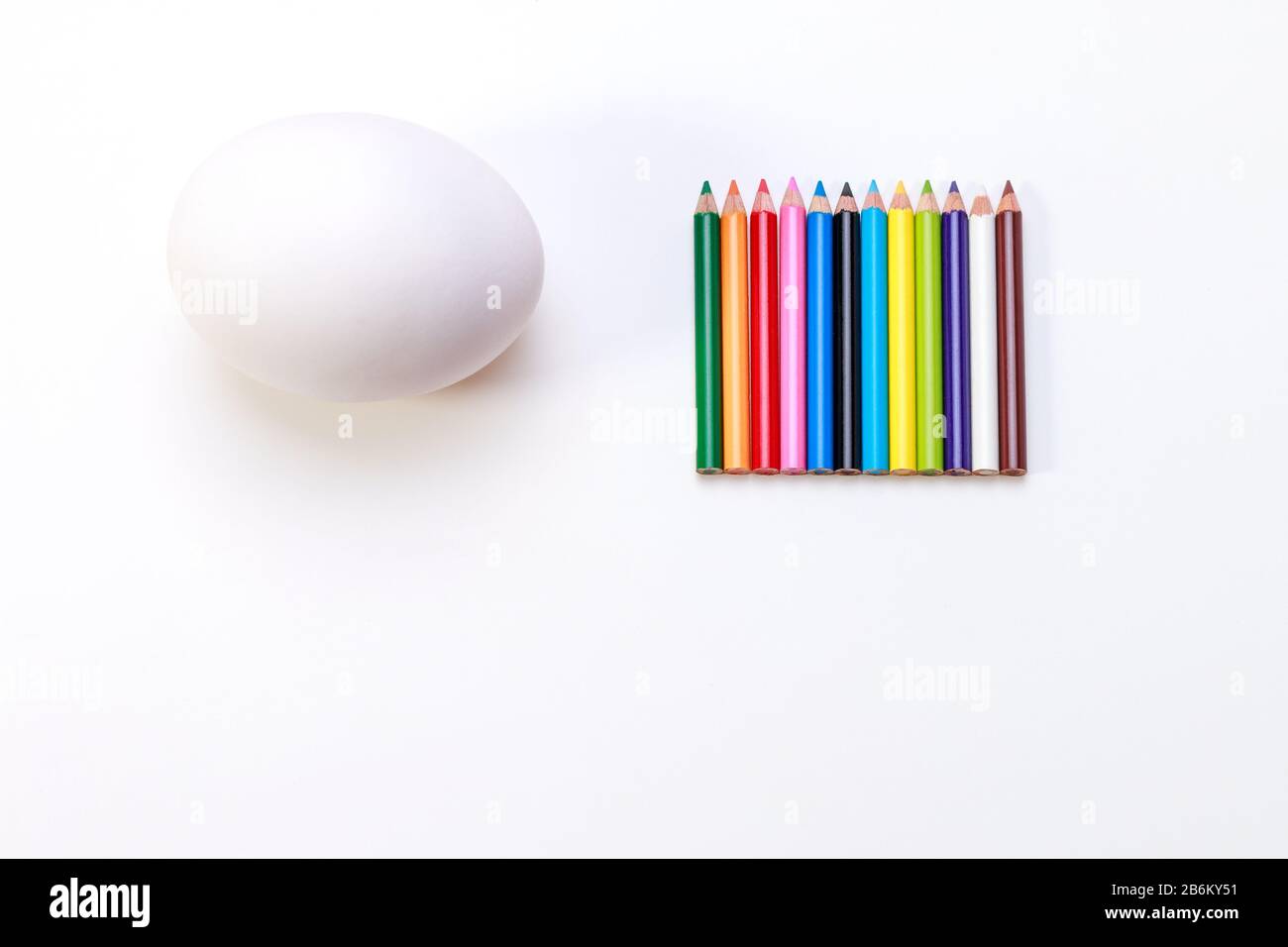 a snow white Easter egg ready to be colored by a set of colorful ...