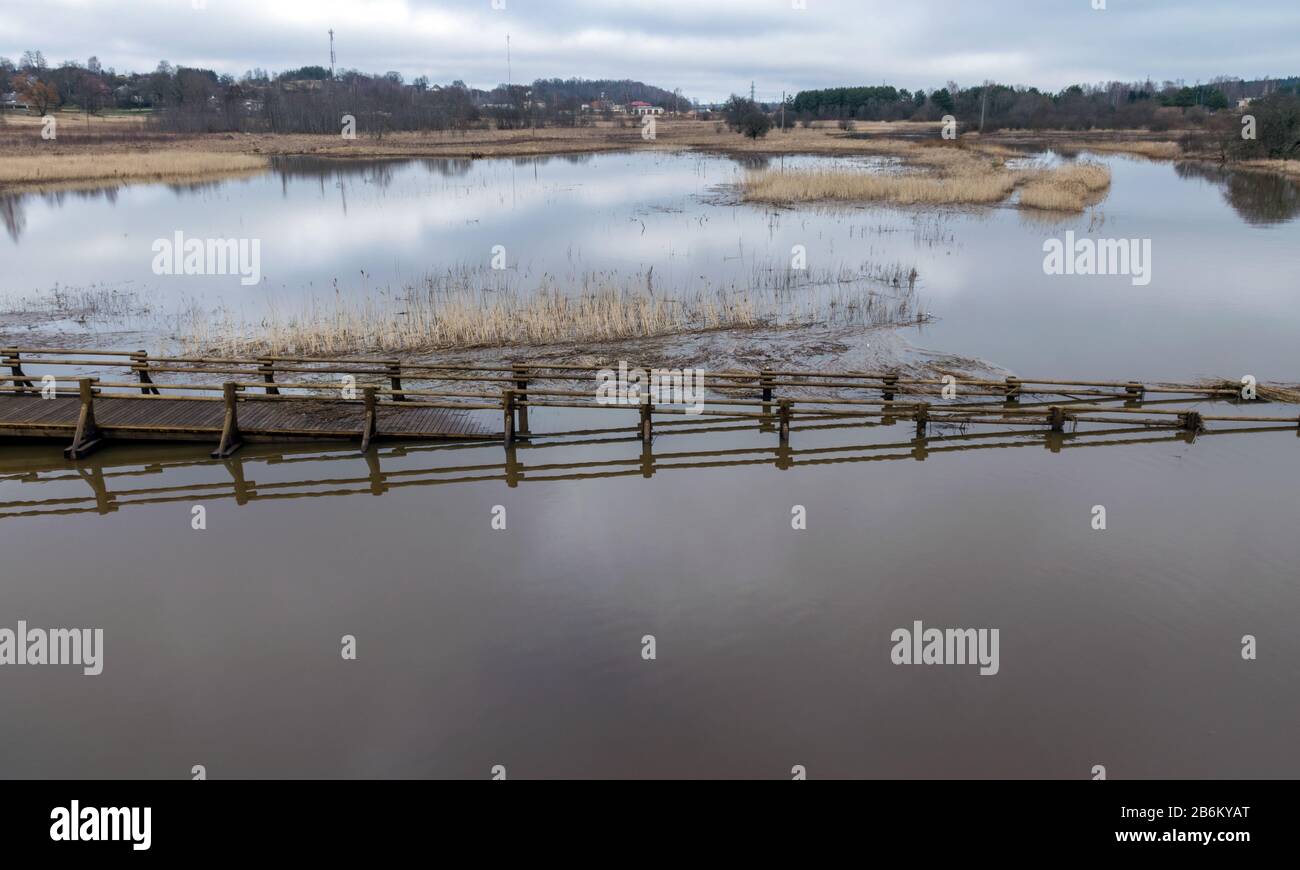 landscape with overflowing river in spring, wooden pedestrian ...