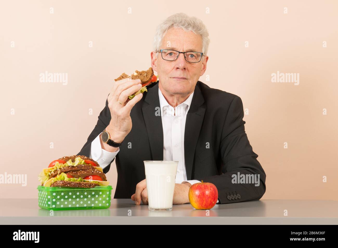 Senior business man eating his bread meal at the office Stock Photo - Alamy