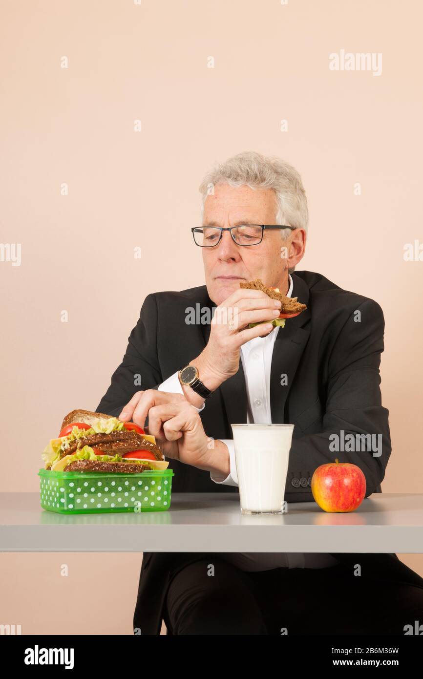 Senior business man eating his bread meal at the office Stock Photo - Alamy