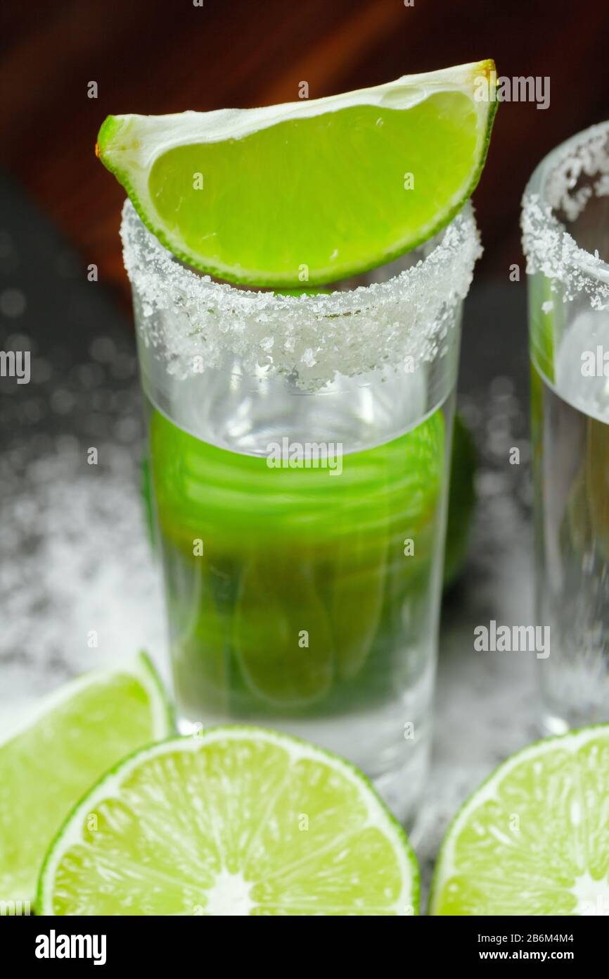 Tequila silver shots with lime slices and salt on wooden board Stock ...