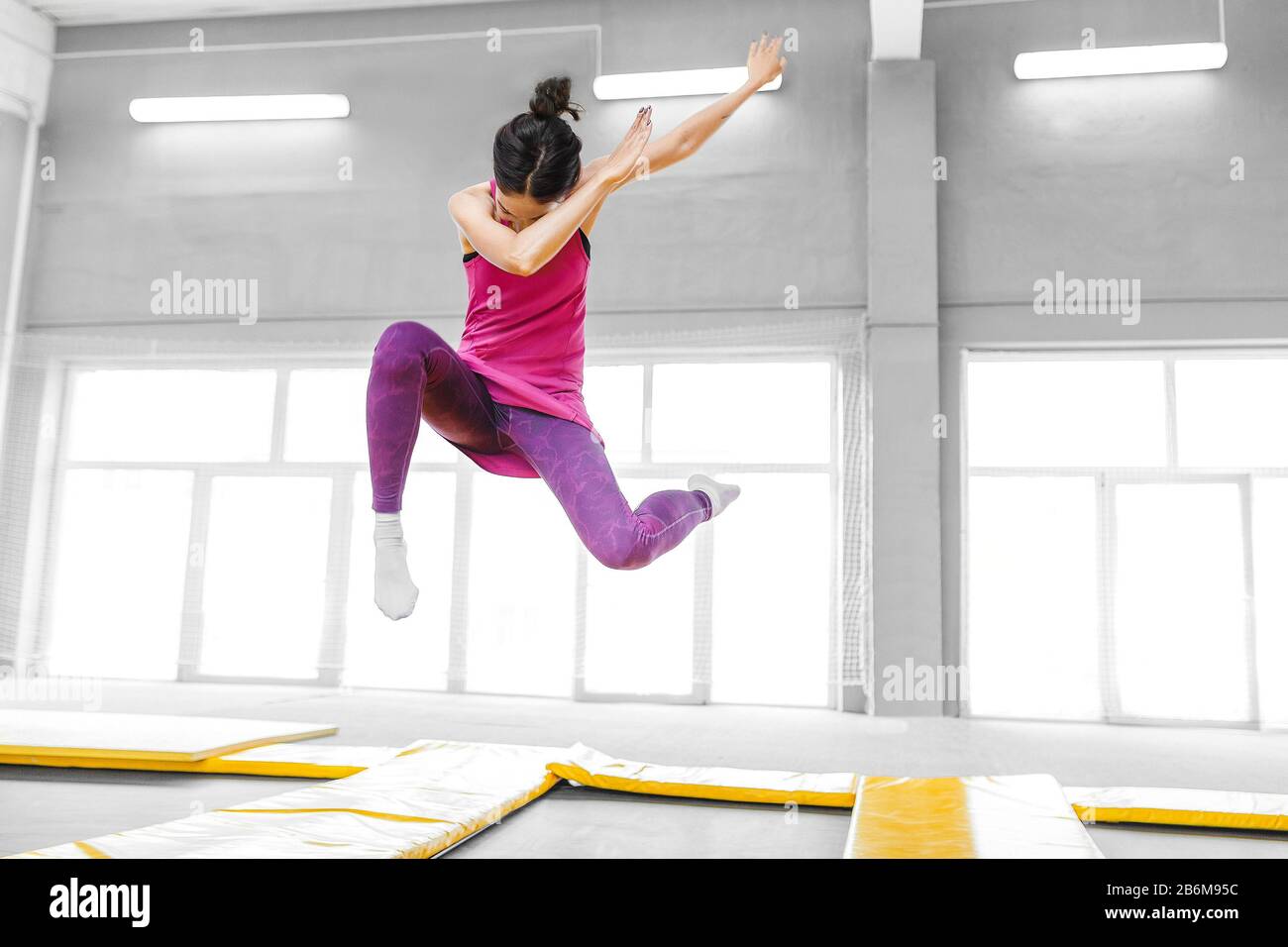 modern hip-hop woman dancer jumping and doing dab in trampoline fitness ...