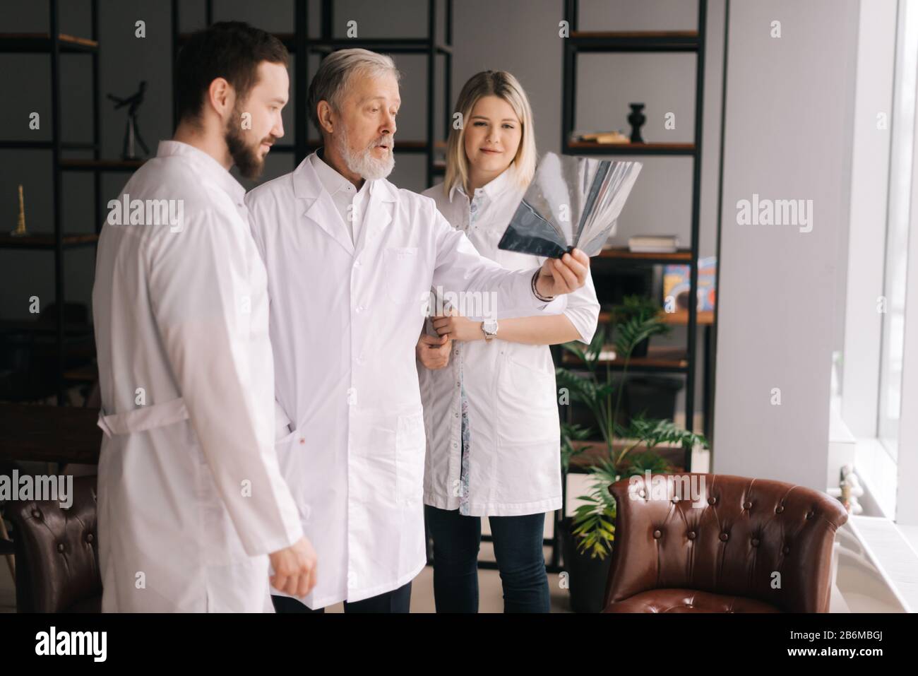Medical team of three doctors examining X-ray scan together Stock Photo ...