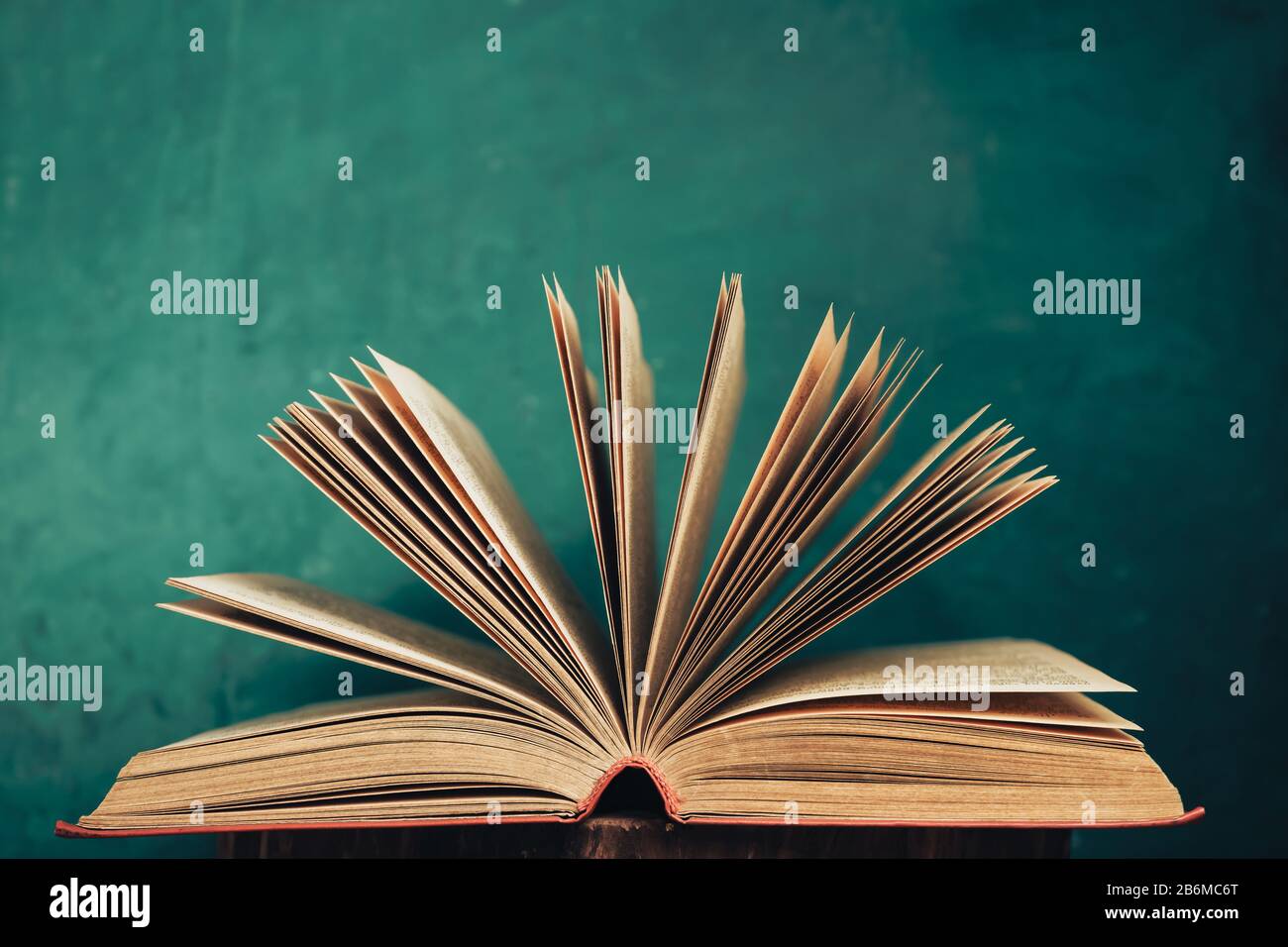 Old open book on a old wooden table and Green wall background behind ...