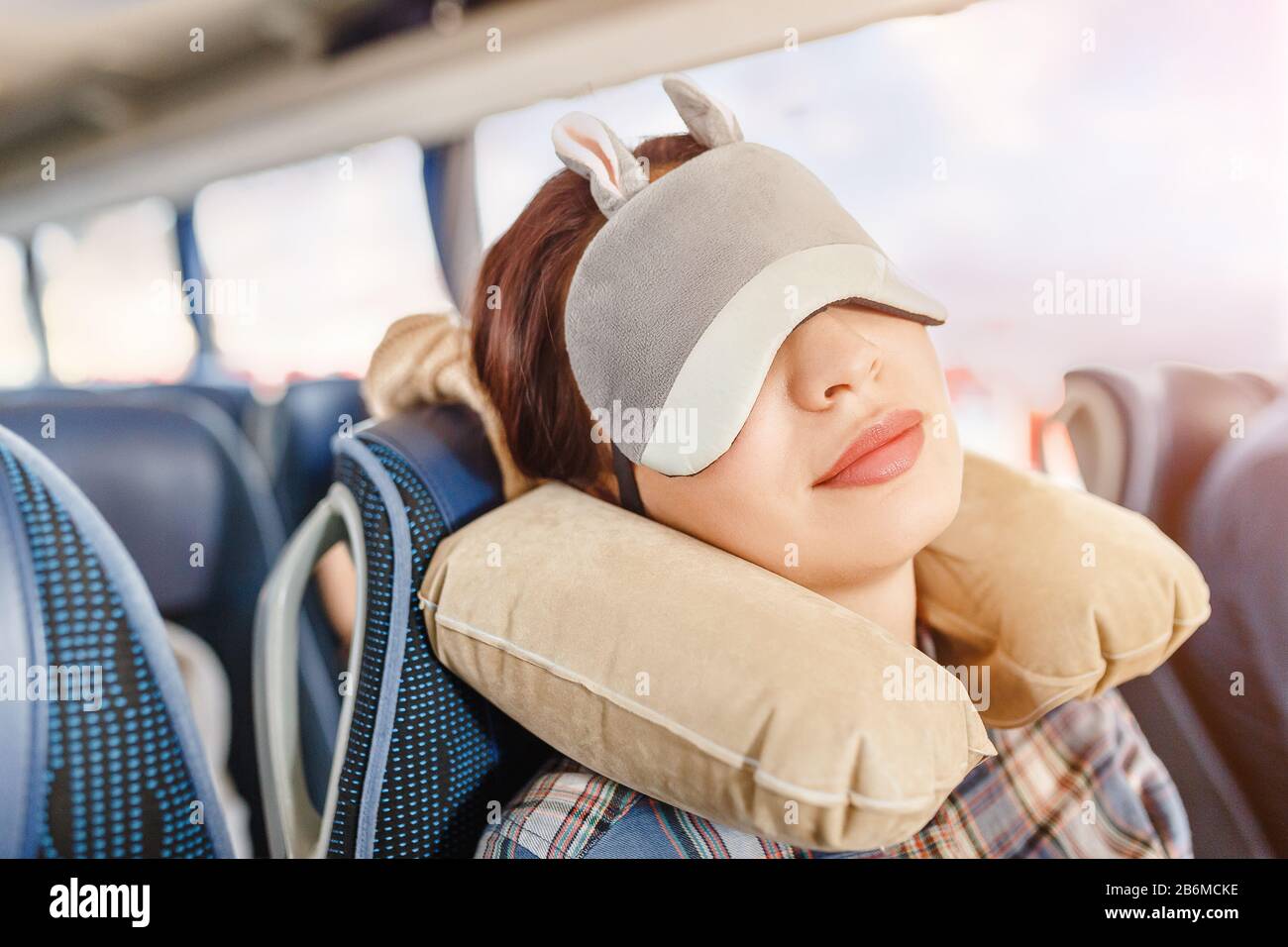 Womang in sleep mask and with pillow travelling in bus Stock Photo - Alamy