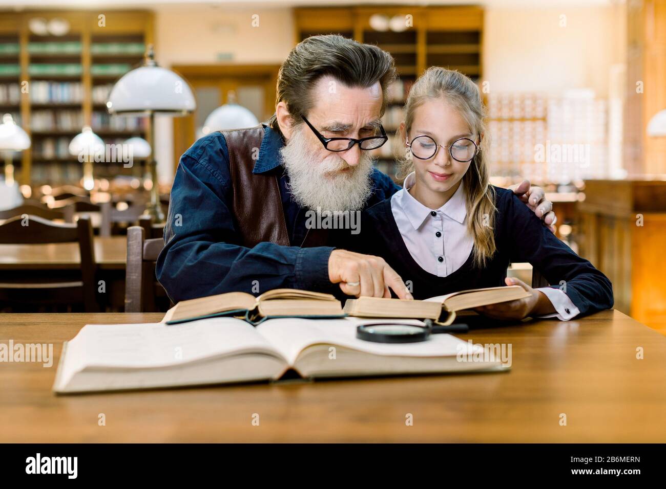 Grandfather reading together with his granddaughter a book hi-res stock ...