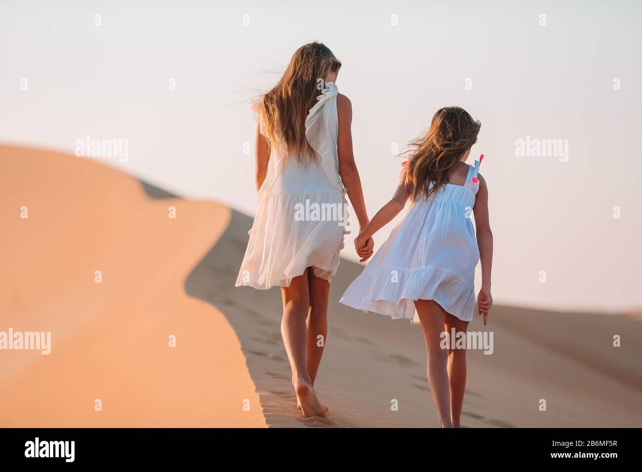 Girls among dunes in big desert in Emirates Stock Photo - Alamy