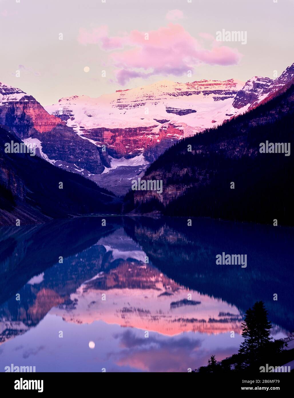 View of lake with forest and mountains reflected in water, Banff ...