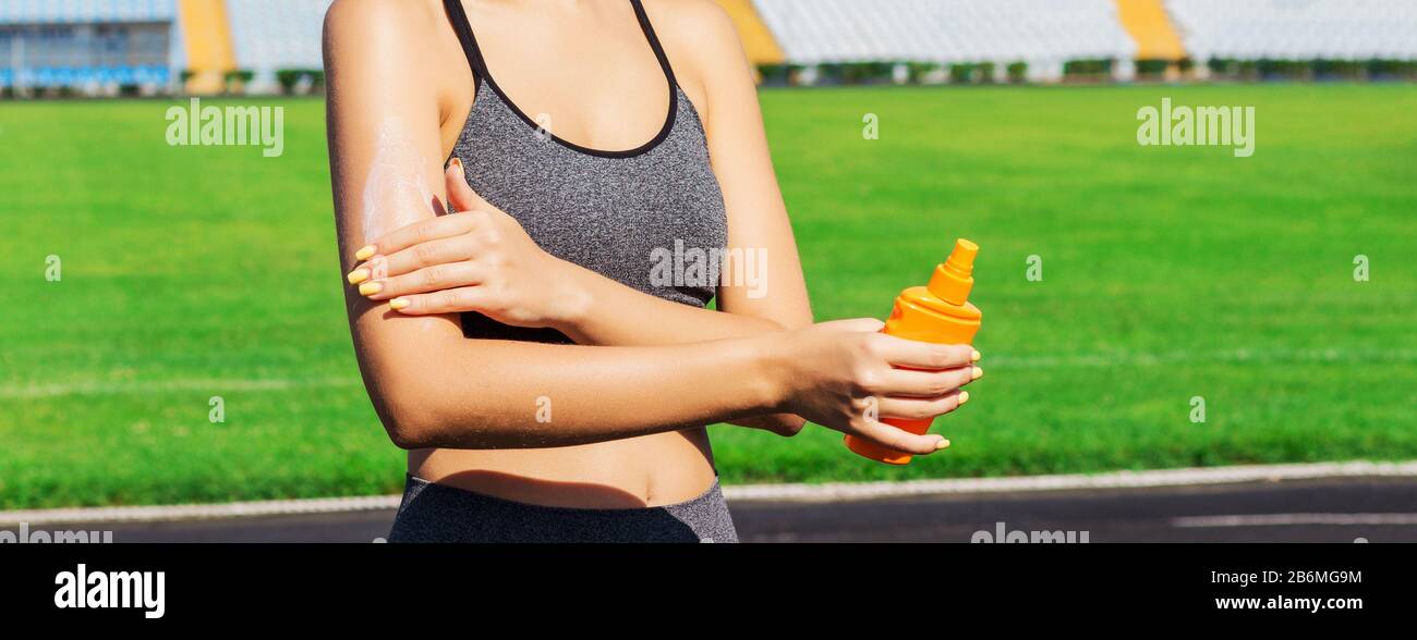 Young woman is applying sunscreen on her arms before physical ...