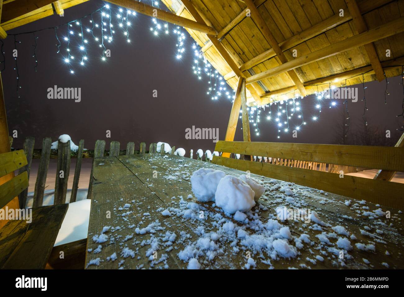 Close-up three snowballs lie on a wooden table under roof of arbor with ...