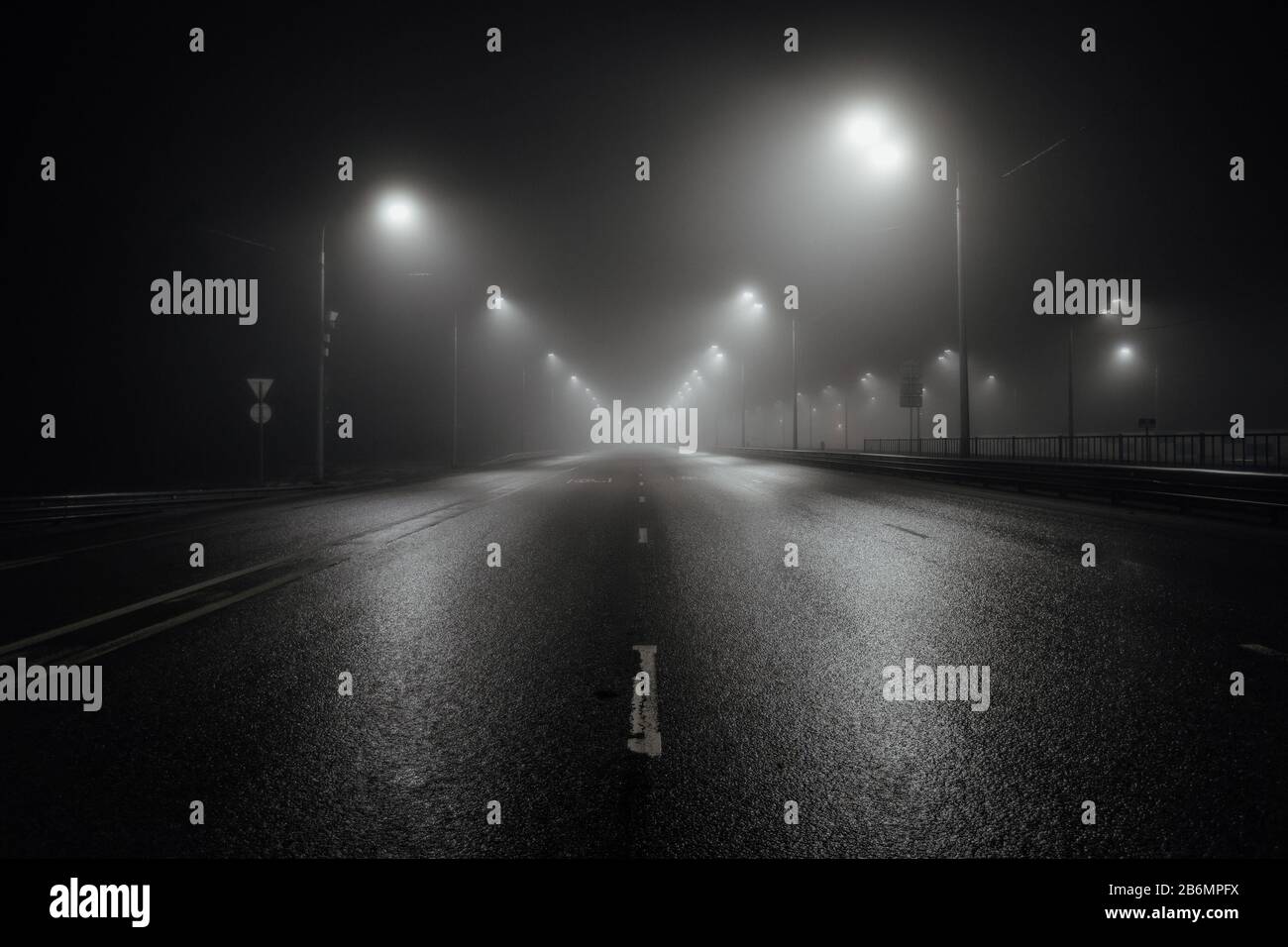 Foggy misty night road illuminated by street lights Stock Photo - Alamy