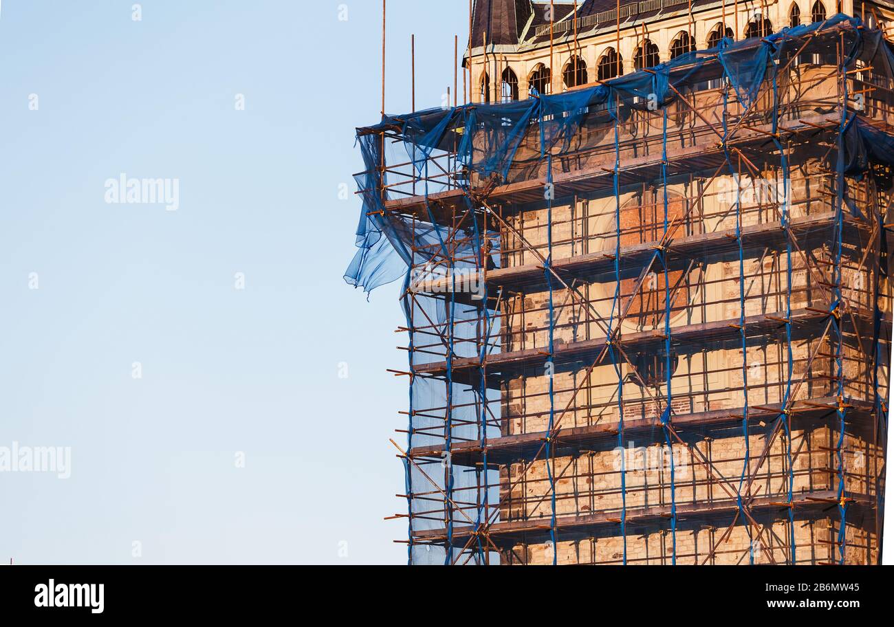 Workers are engaged in the restoration of the old tower with beautiful ...
