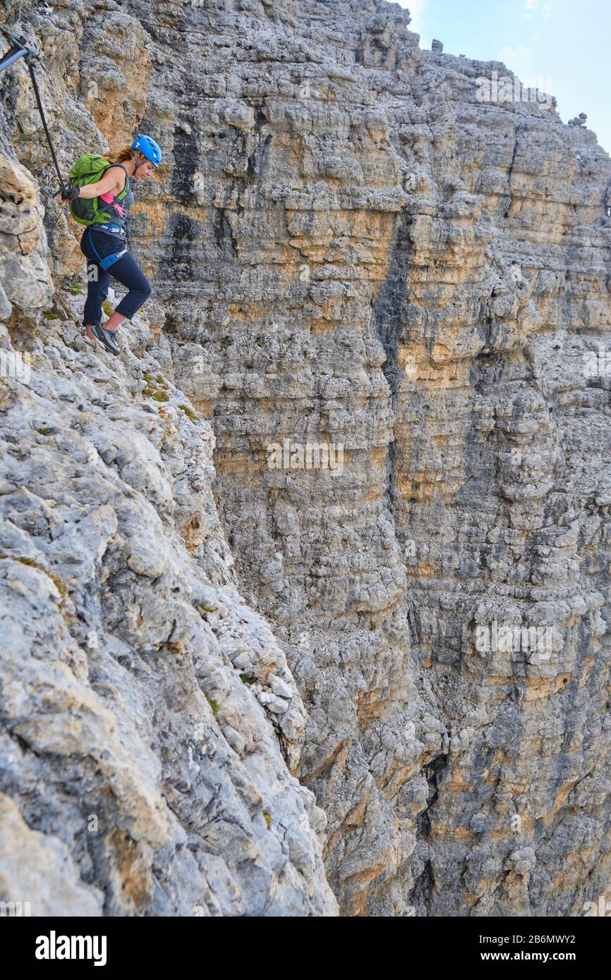 Courageous female climber looking down from high up on via ferrata ...