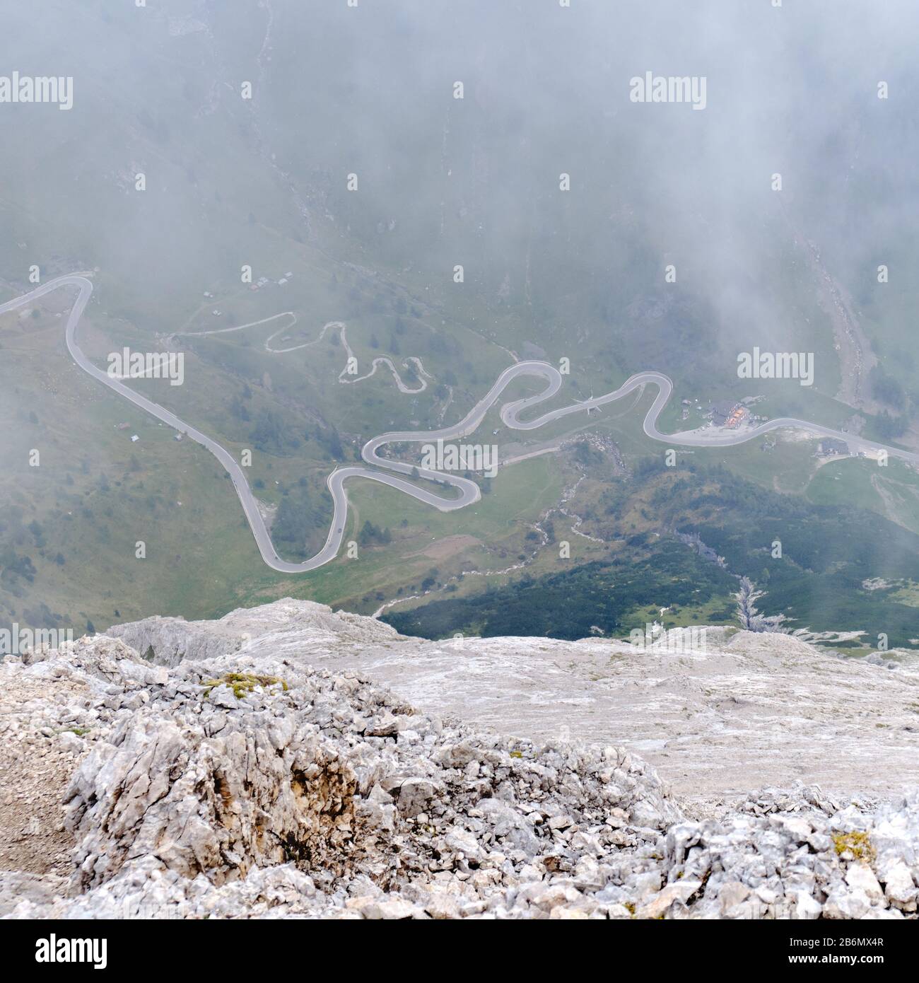 Winding road in fog at Pordoi pass, Dolomites mountains, Italy. View ...