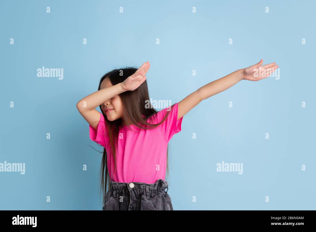 Dabbing, dab. Caucasian little girl's portrait on blue studio ...