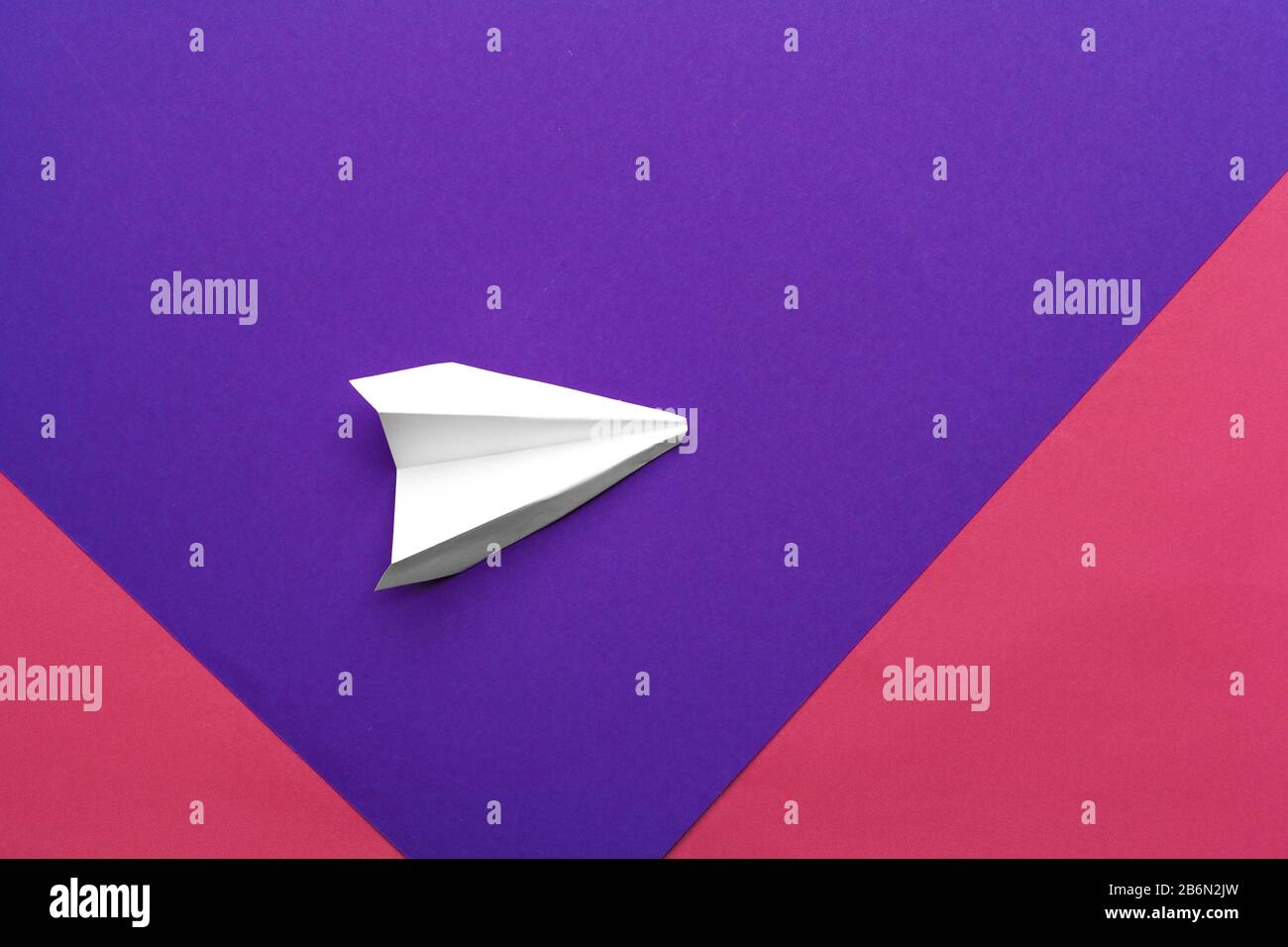white paper airplane on a color block paper background Stock Photo - Alamy