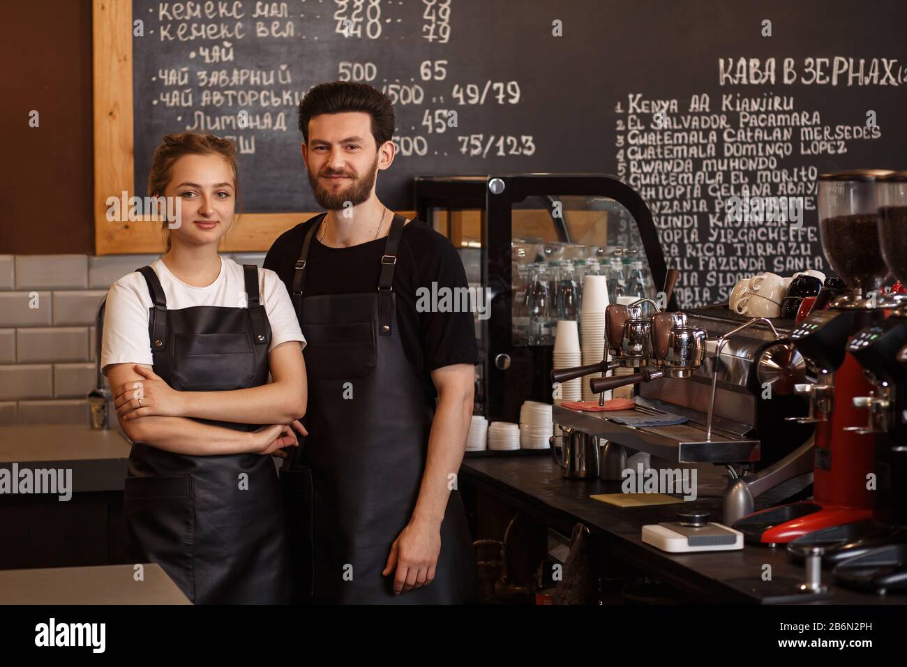 Two young smiling barista at work. Professional barista team brewing ...