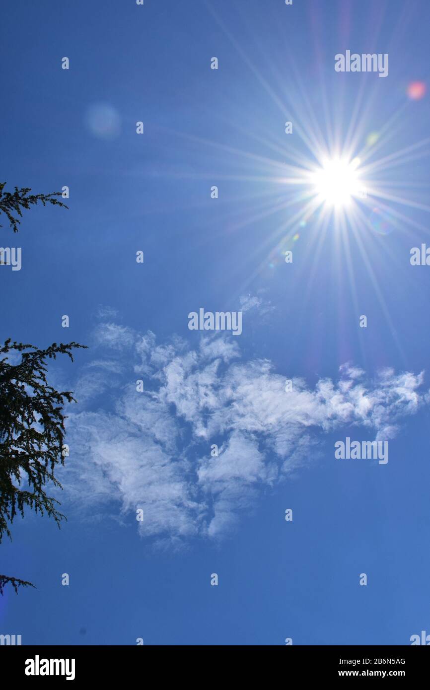 Sun at zenith at noon in blue sky with little clouds Stock Photo - Alamy