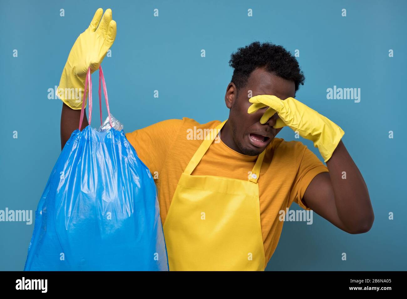 African american black young guy holding a blue bag of trash. Studio ...