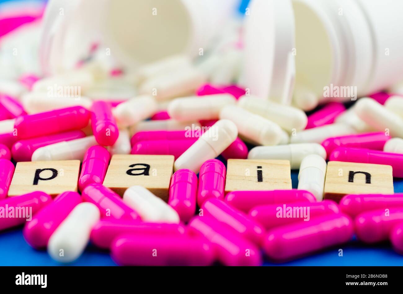 The word PAIN on the background of scattered pink and white capsules ...