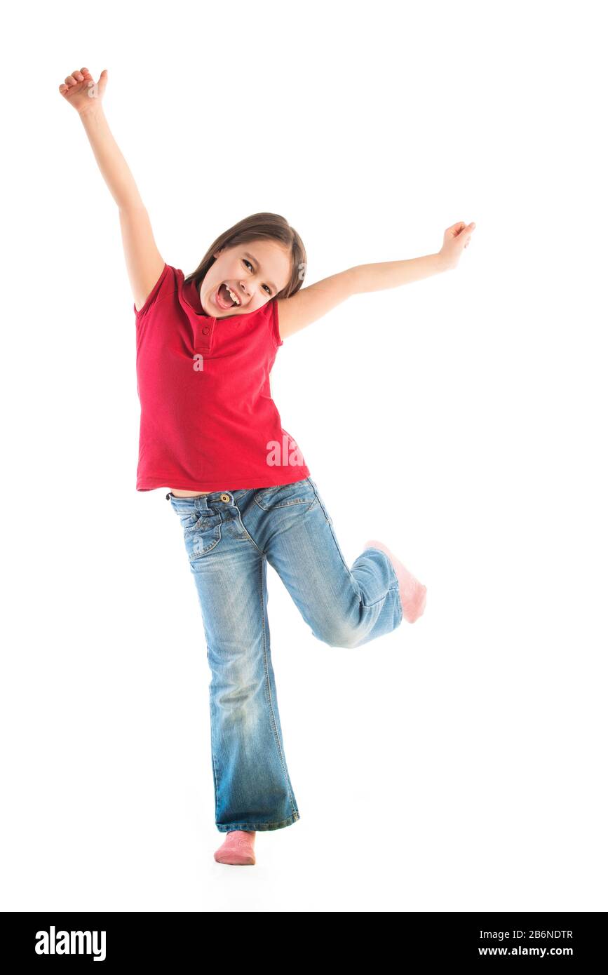 Happy child posing in childrens clothes standing on one leg, arms ...