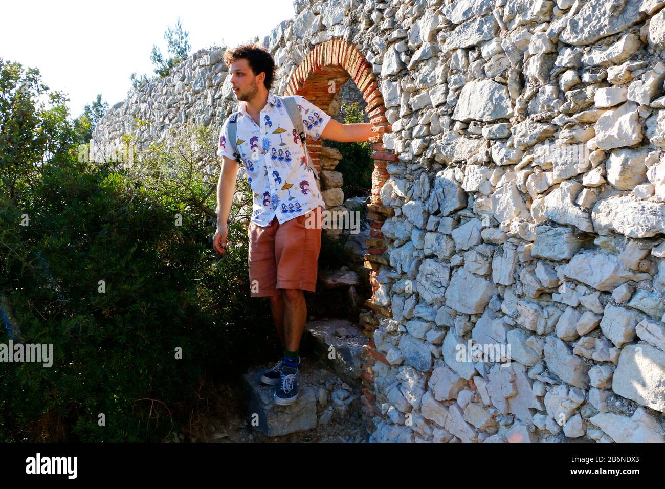 Mae model in hawaii shirt stepping through a historic door in southern ...
