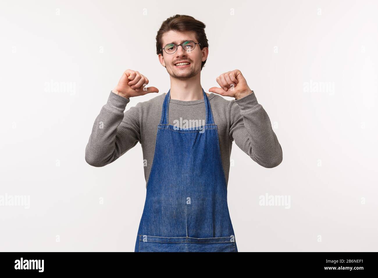 Portrait of cool and arrogant young male employee in apron brag he can ...