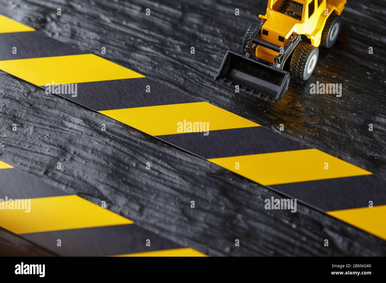 Yellow toy bulldozer on a black background texture. Black and yellow ...