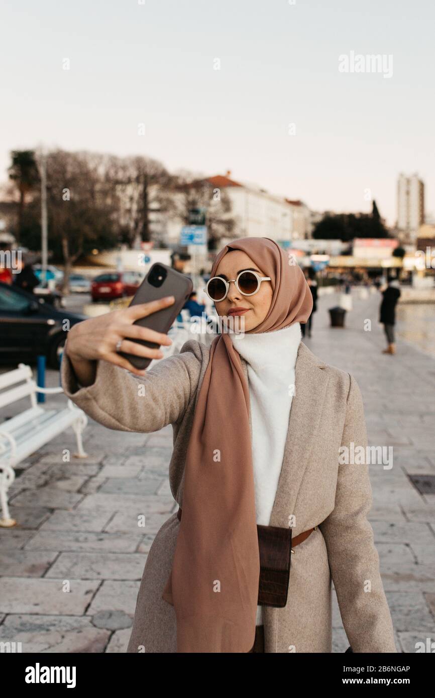 Beautiful portrait of European Muslim women with hijab holding mobile ...