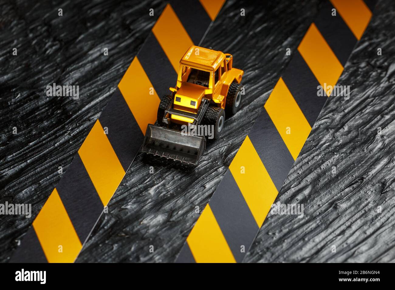Yellow toy bulldozer on a black background texture. Black and yellow ...