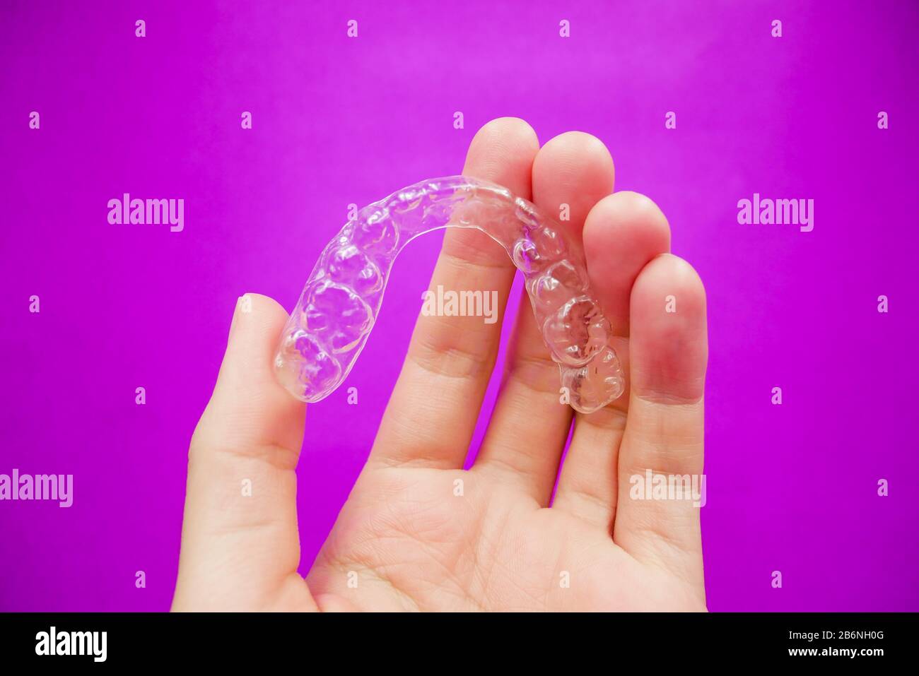 hand holding clear plastic retainer teeth that isolated on purple ...