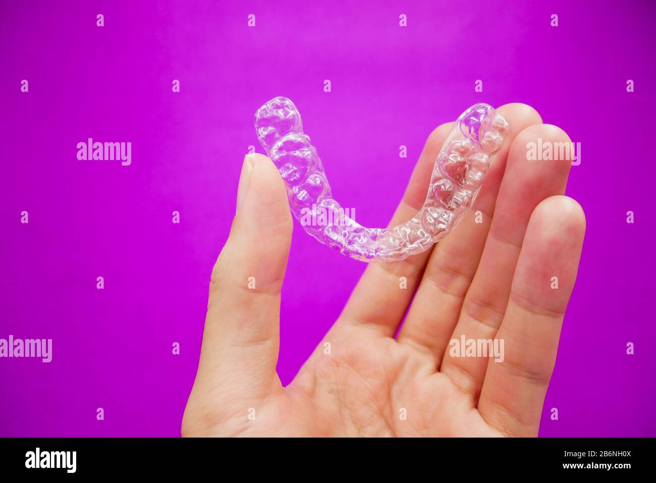 hand holding clear plastic retainer teeth that isolated on purple ...