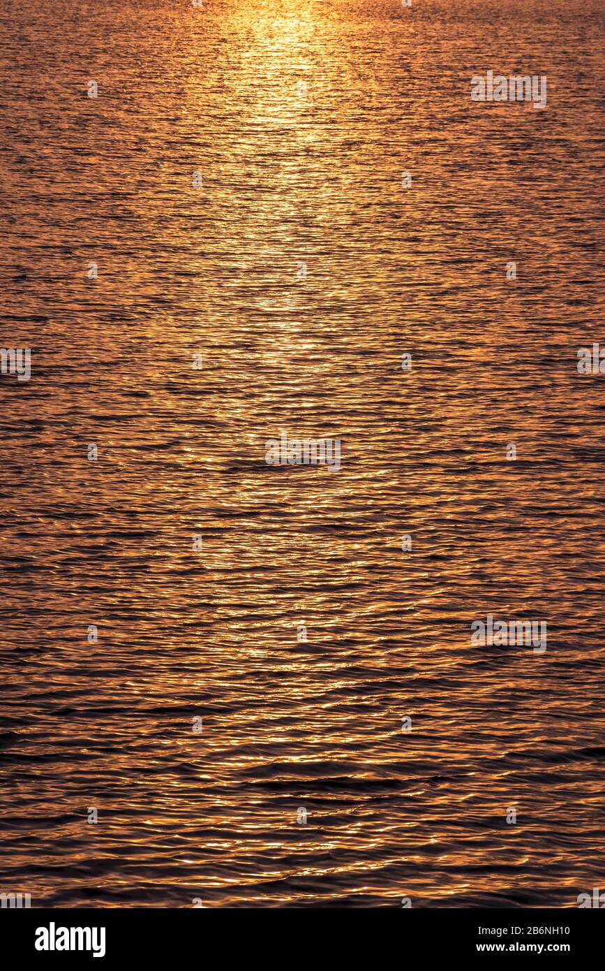 The sun sets on the pacific ocean. High contrast textures on the waves ...