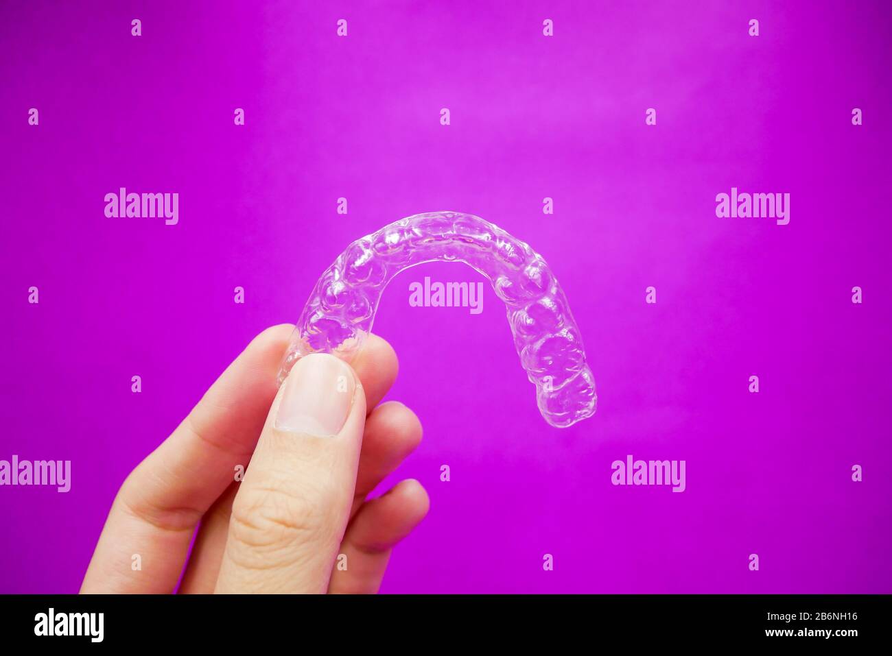 hand holding clear plastic retainer teeth that isolated on purple ...