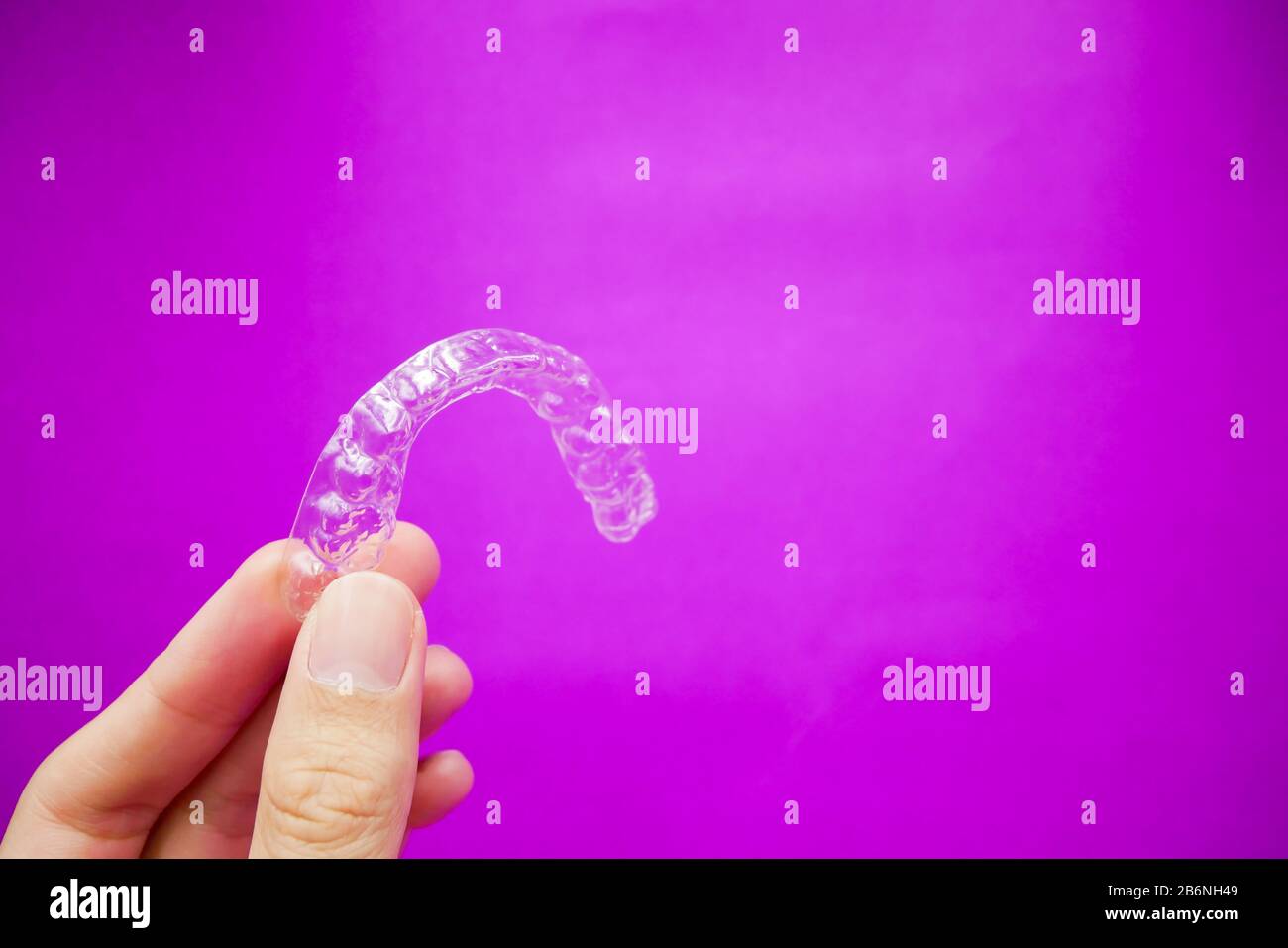 hand holding clear plastic retainer teeth that isolated on purple ...
