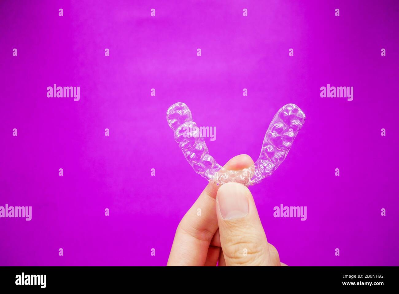 hand holding clear plastic retainer teeth that isolated on purple ...