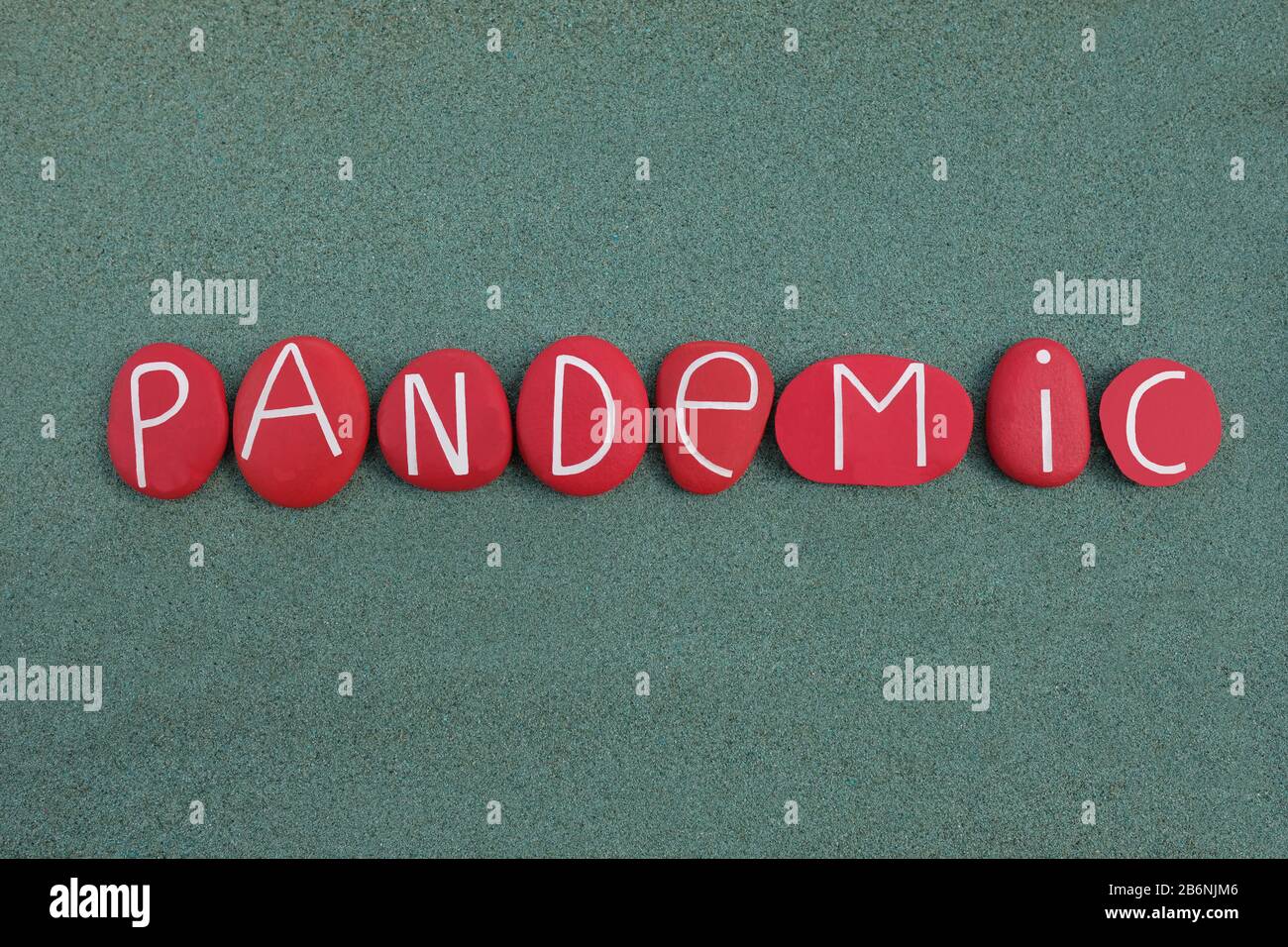 Pandemic word composed with red colored stone letters over green sand ...