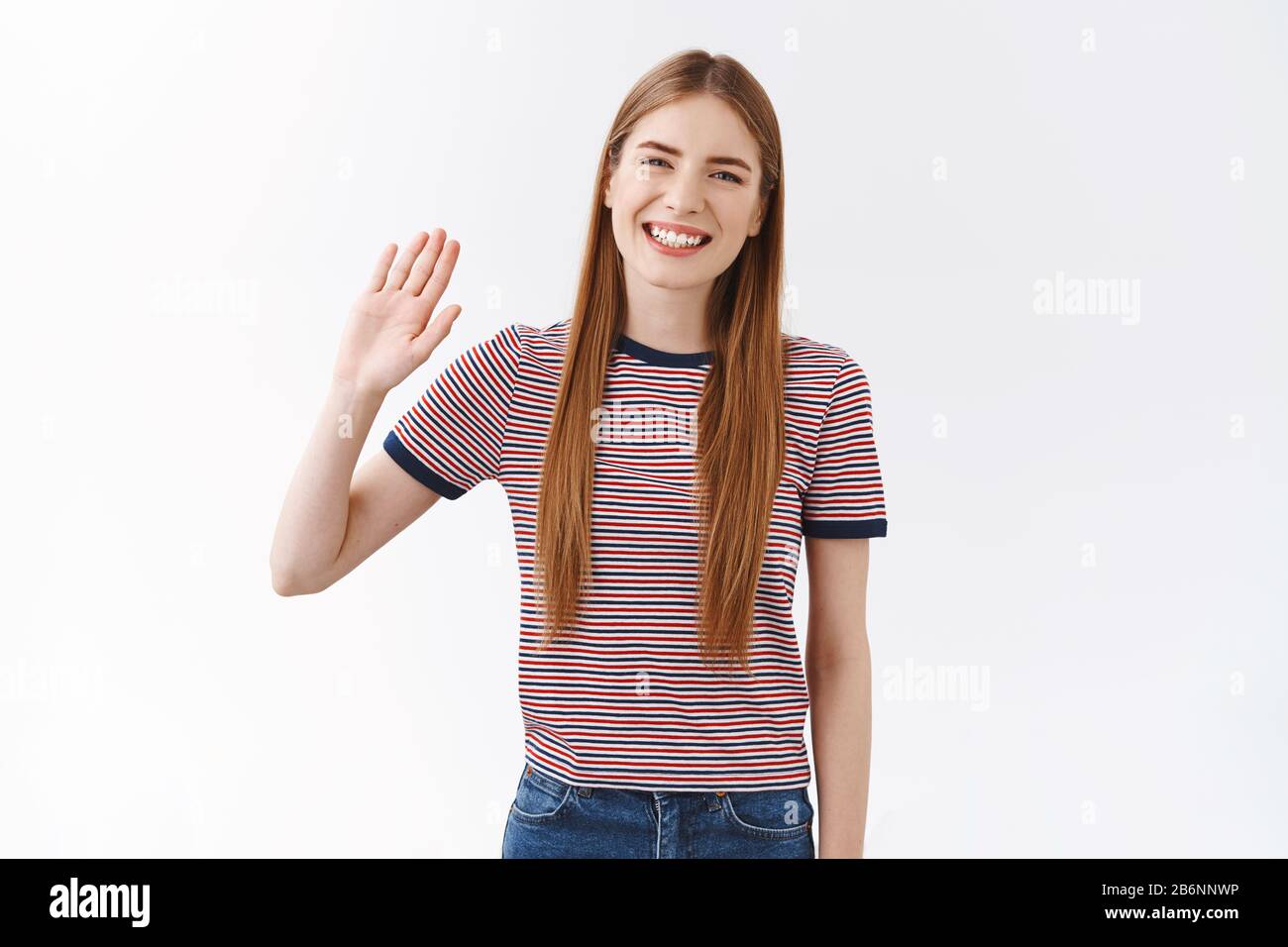 Friendly positive, cute young caucasian girl in striped t-shirt raising ...