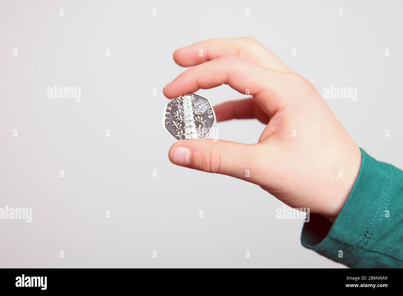 A child's hand holding a rare 2009 Kew gardens 50p between fingers, 50 ...
