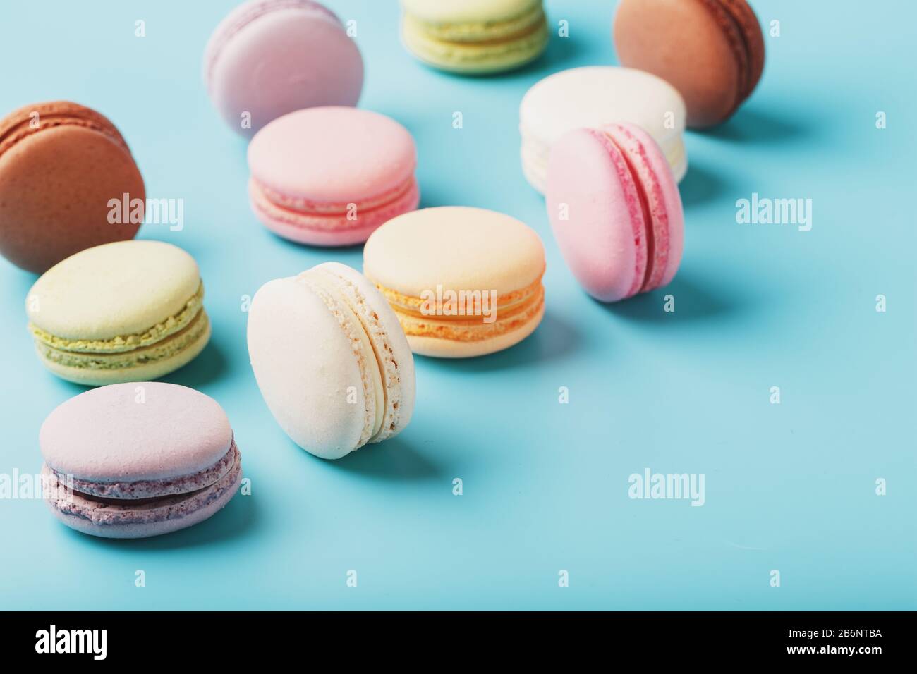 Macaroni cookies of different colors are scattered on a blue background ...