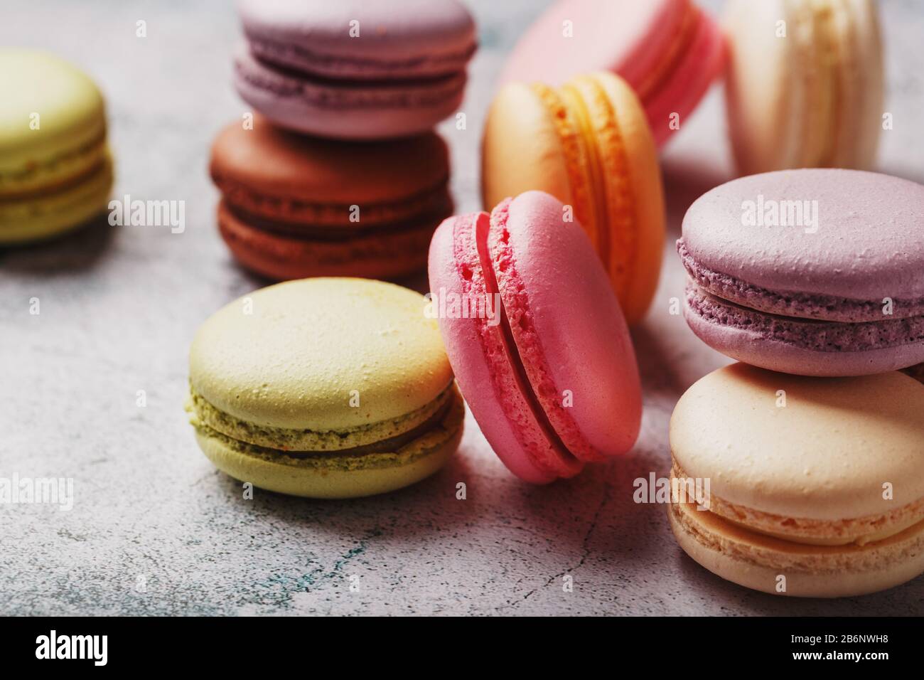 Macaroni cookies of different colors in a box on a gray textured ...