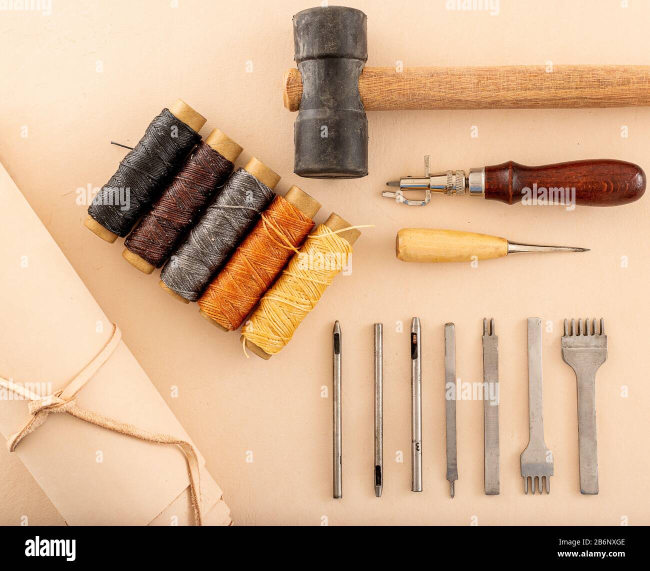 Leather working tools and rolled up hide organized Stock Photo - Alamy