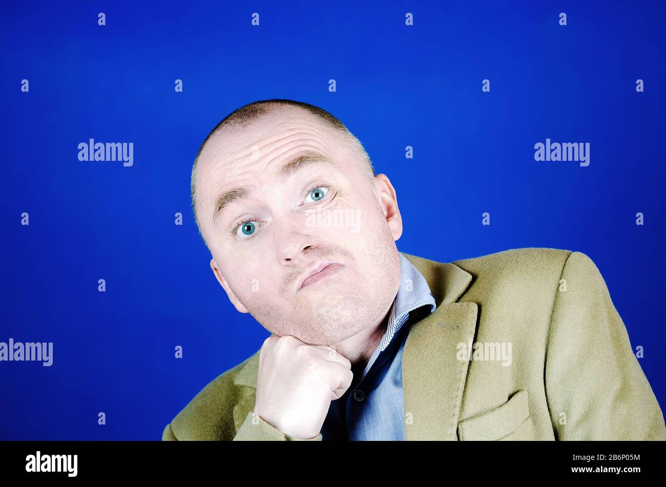 A confused or surprised young man with blue eyes put his fist under his ...